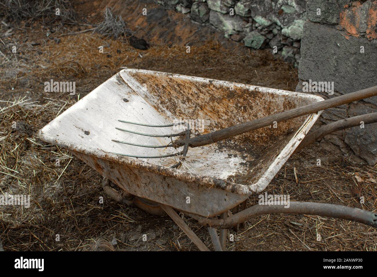 Dirty wheelbarrow on countryside, maybe on a farm, with rake inside ...