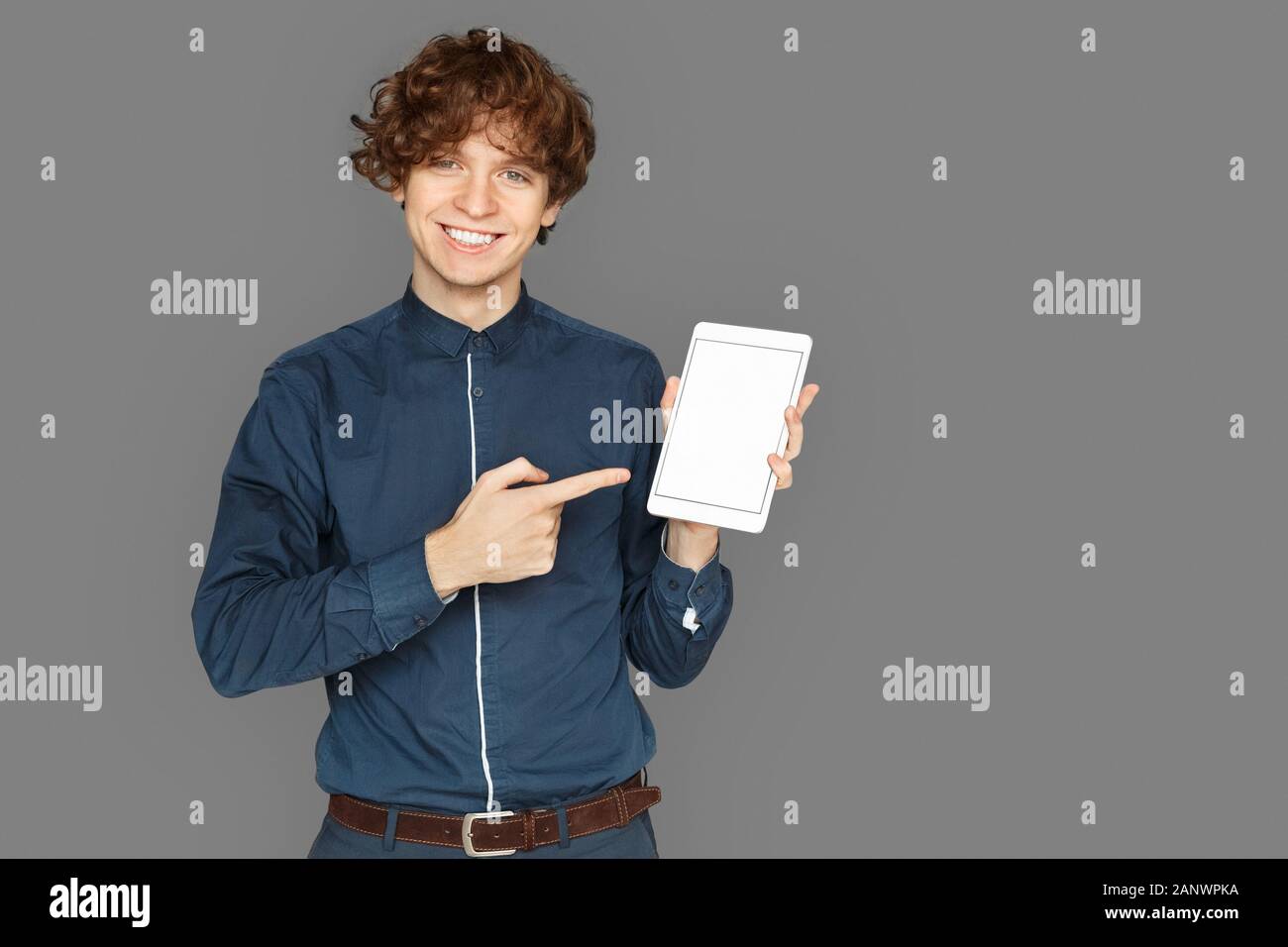 Freestyle. Teenager boy standing isolated on grey pointing at screen of ...