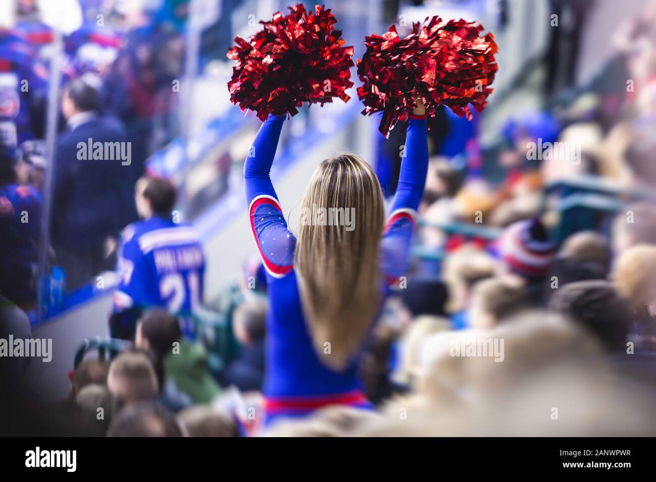 Female cheerleader in red blue uniform with pom-pom with audience in ...