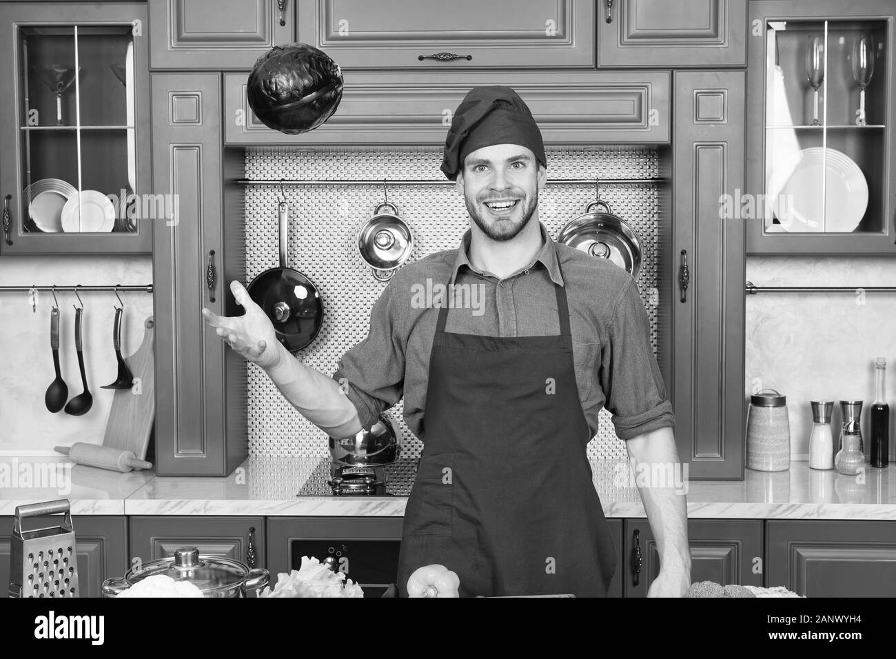 Catch it. Handsome cook in kitchen. Chef following recipe. Cooking ...