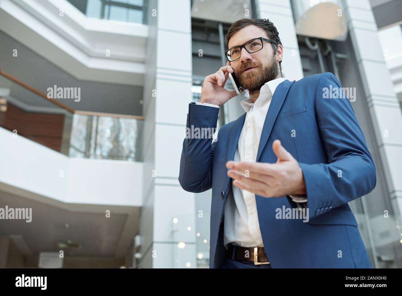Young confident male business agent in elegant suit consulting one of ...