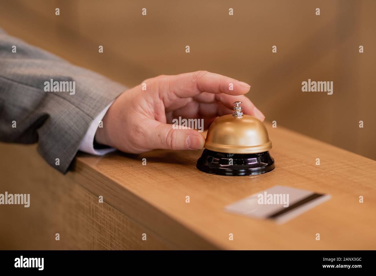 Hand of traveling businessman pushing ring button on wooden reception ...