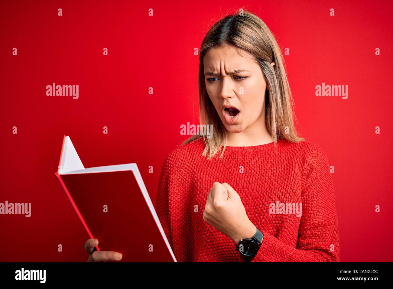 Young beautiful woman reading book standing over isolated red ...