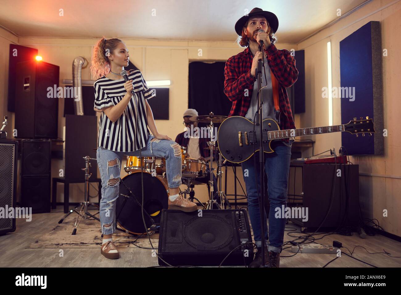 Full length portrait of contemporary music band enjoying singing with ...