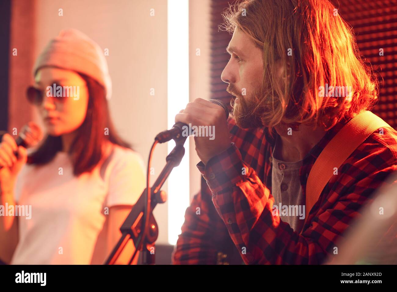 Side view portrait of long-haired young man playing guitar and singing ...