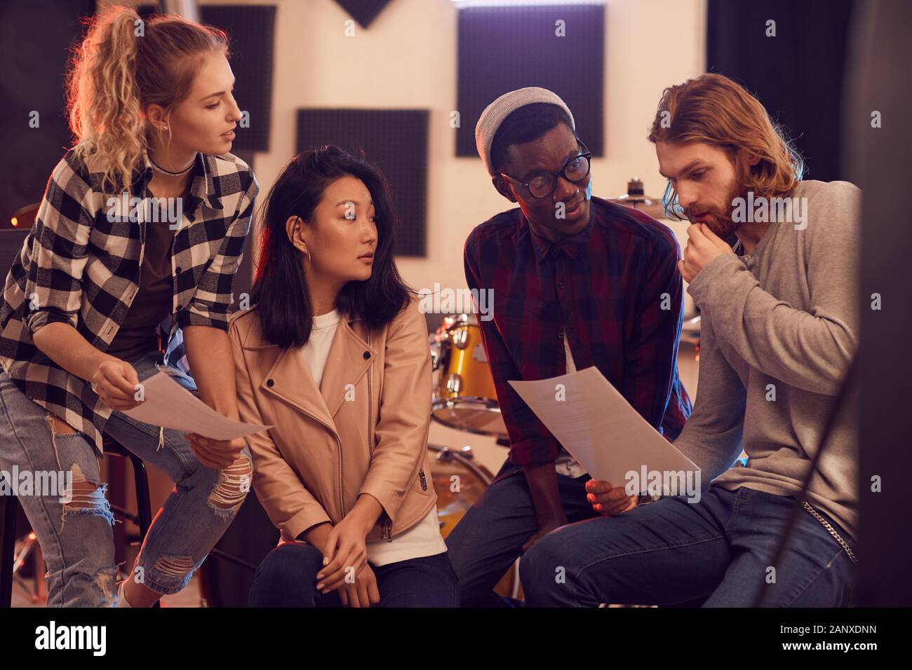 Multi-ethnic group of young people writing music together while ...