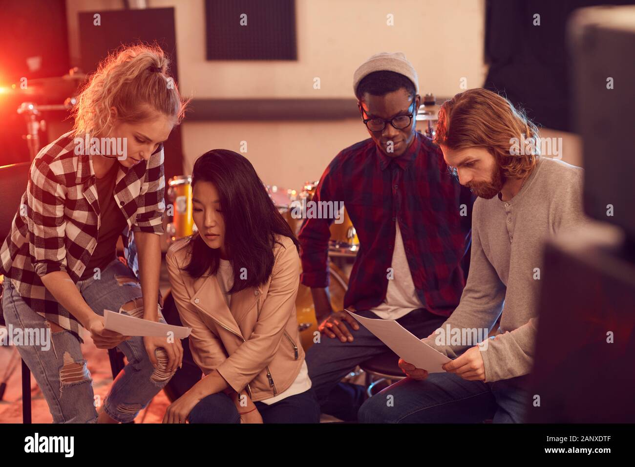 Multi-ethnic group of modern young people writing music together while ...