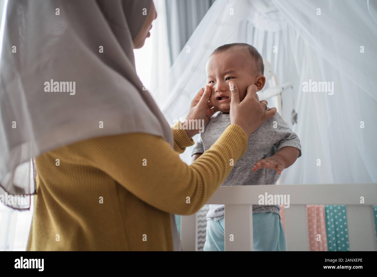 mother try to comfort her cry child at the crib Stock Photo - Alamy