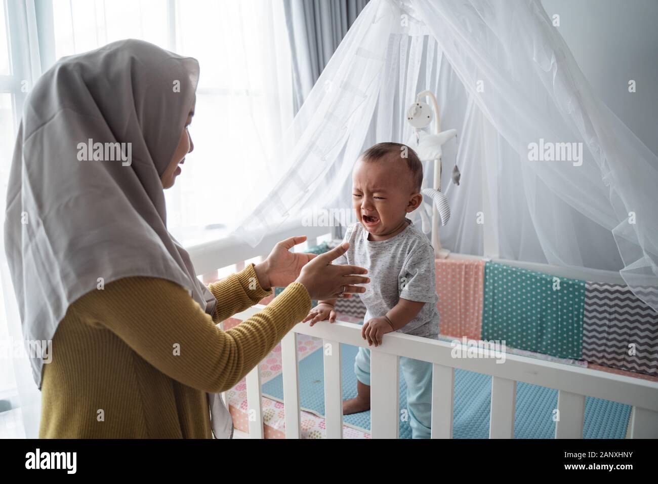 mother try to comfort her cry child at the crib Stock Photo - Alamy