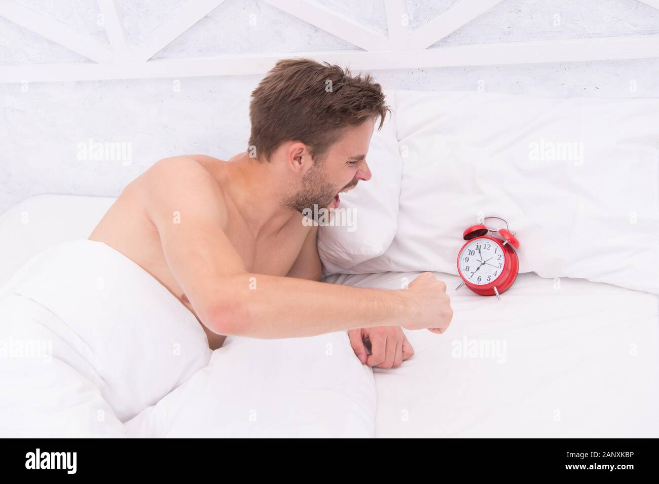 man angry because alarm rings. Angry man lying in bed early in morning ...