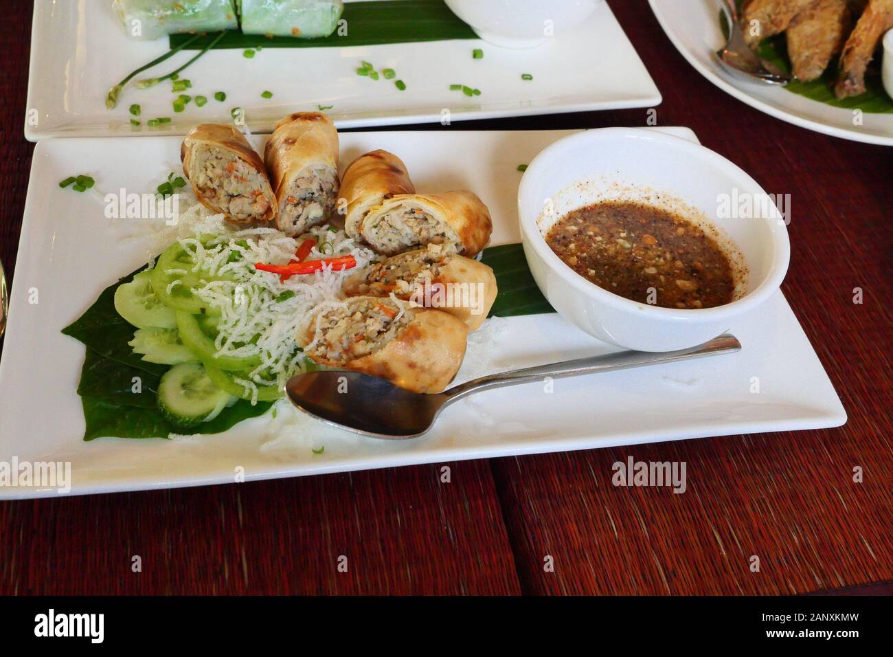 Fried spring rolls with with sliced cucumber and sweet chili sauce in a ...