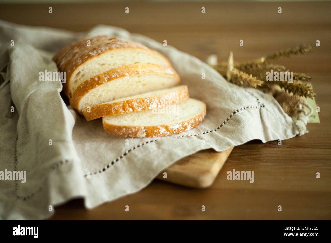 fresh white bread on the linen textile and wooden table with milk glass ...
