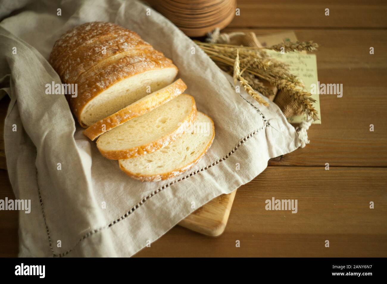 fresh white bread on the linen textile and wooden table with milk glass ...