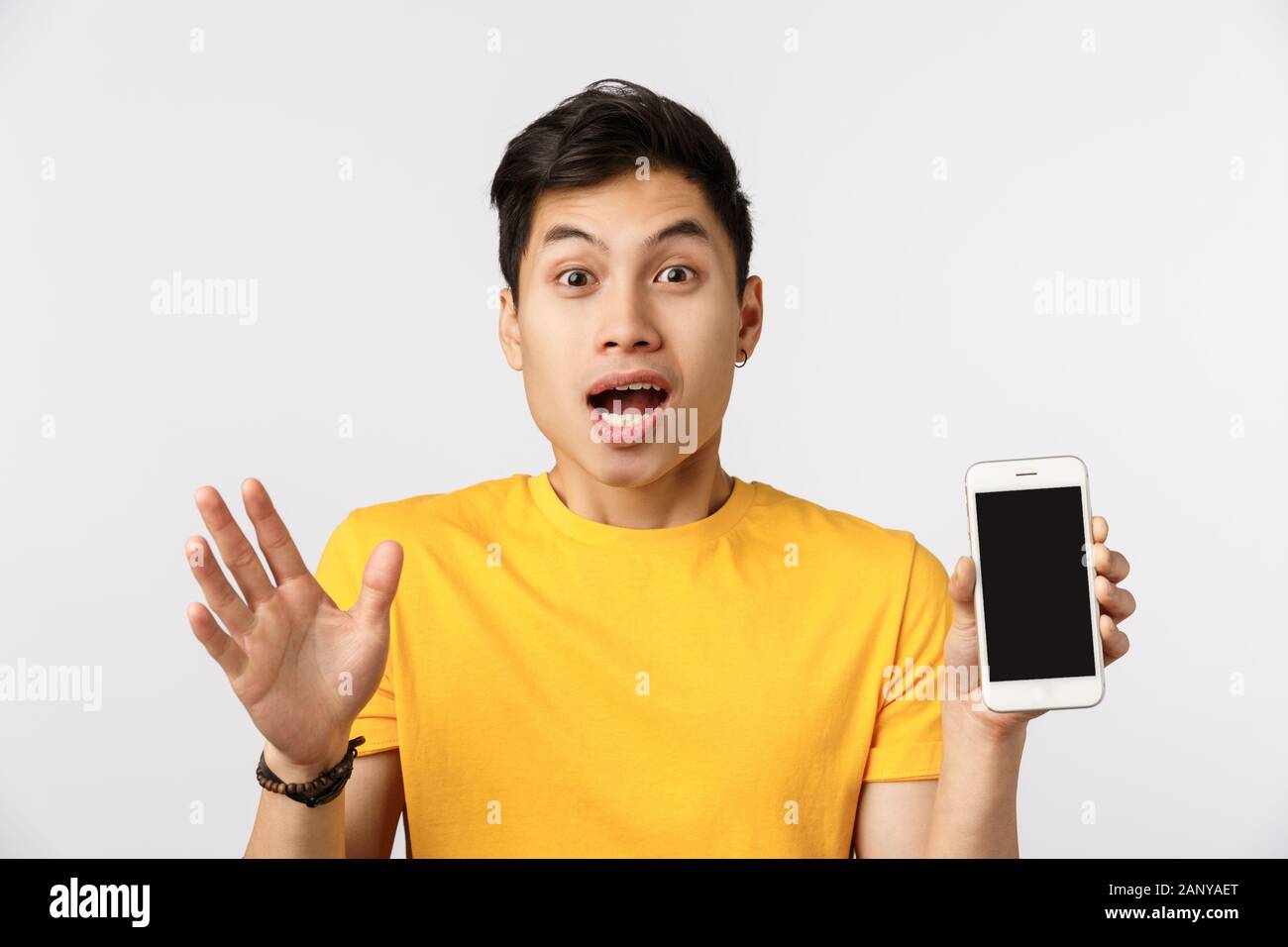 Fascinated, totally impressed young asian man in yellow t-shirt ...