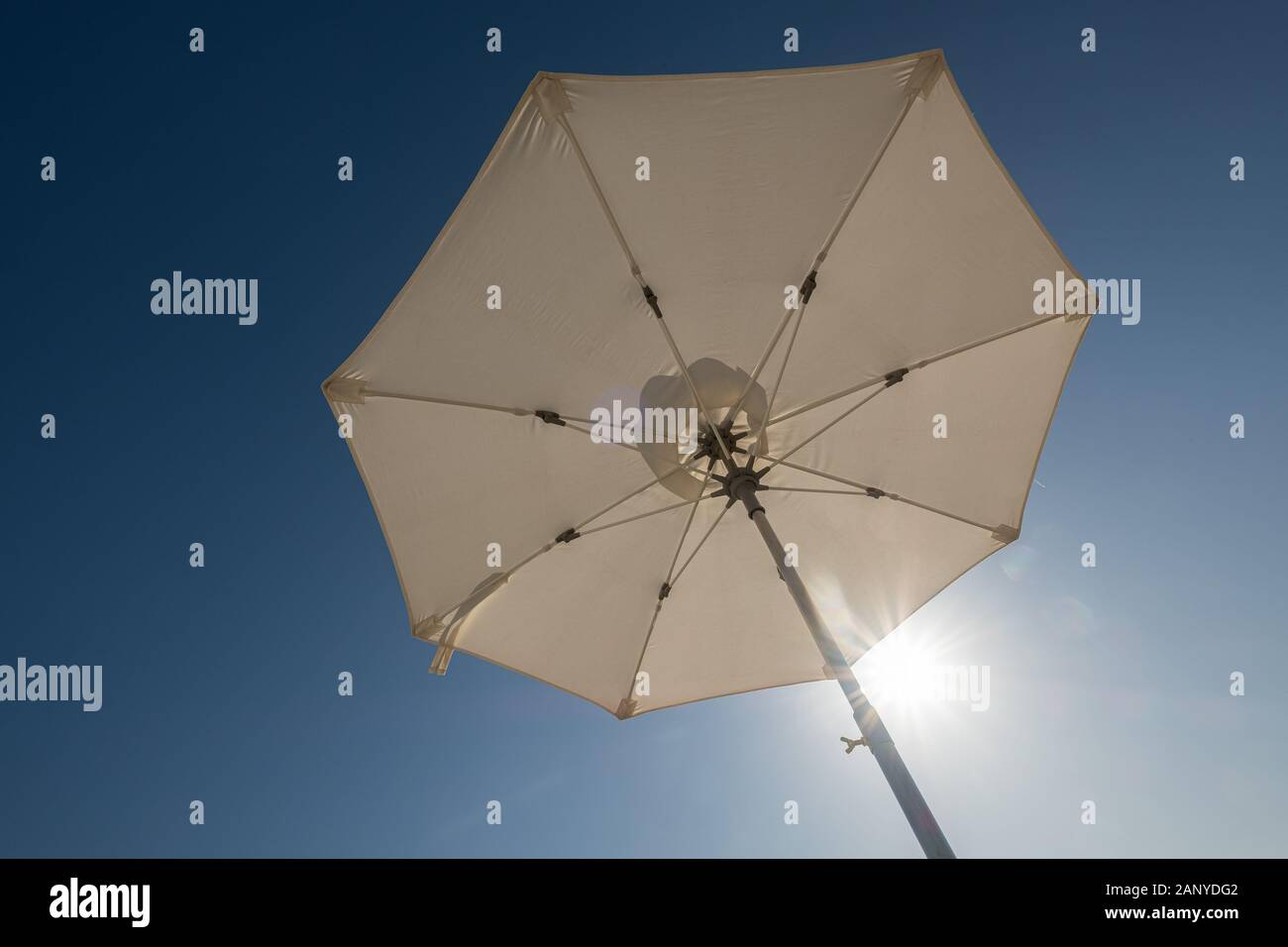 white parasol against sun and blue sky on carihuela beach in ...