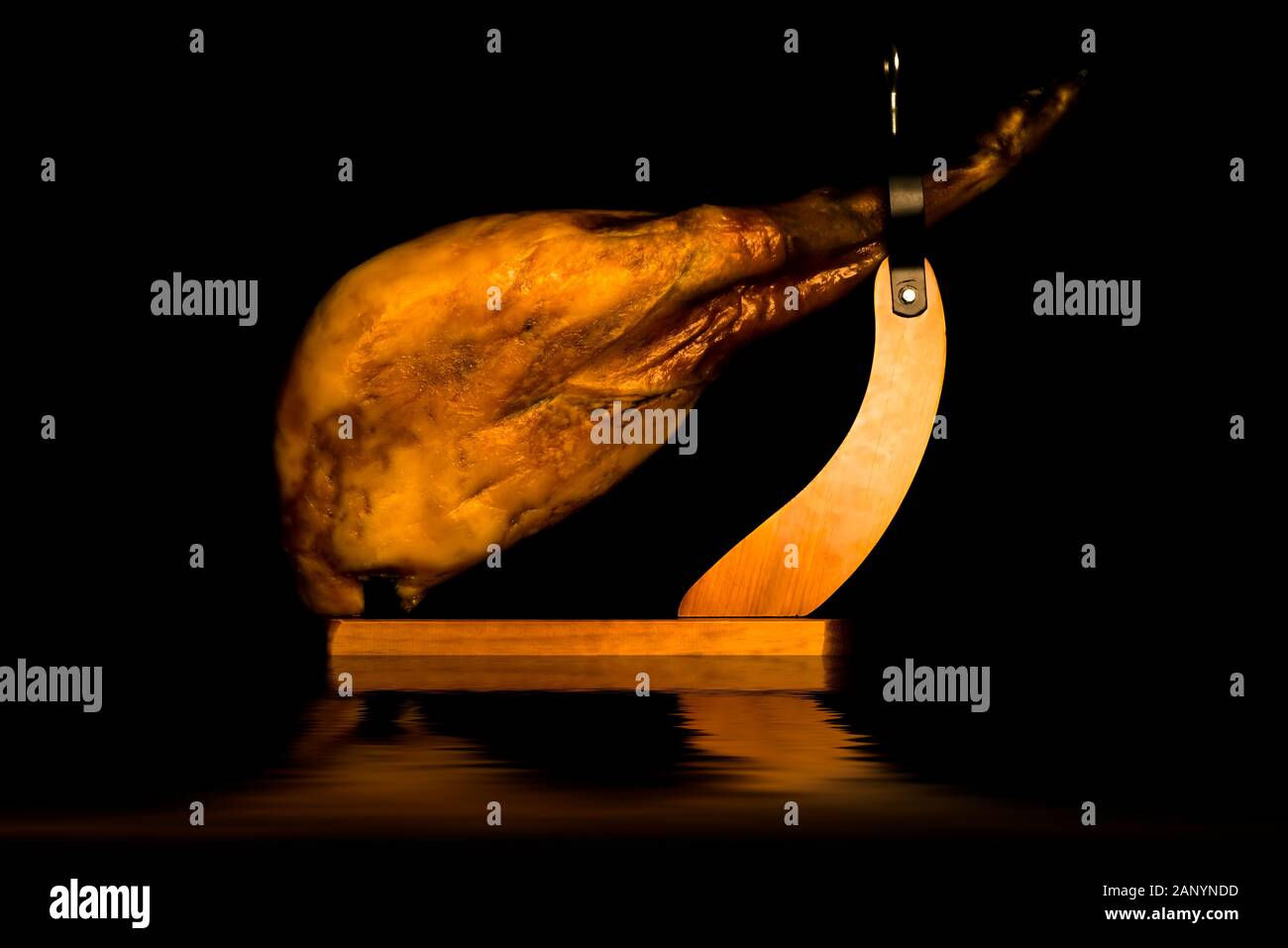 Whole Iberian ham leg in a ham holder reflected on black background ...