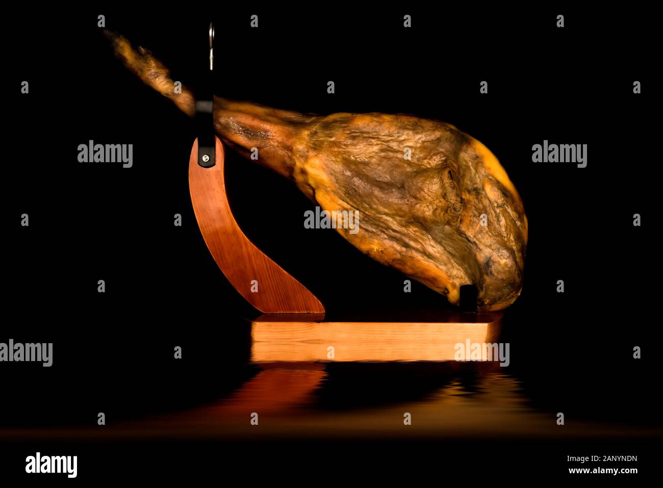 Whole Iberian ham leg in a ham holder reflected on black background ...