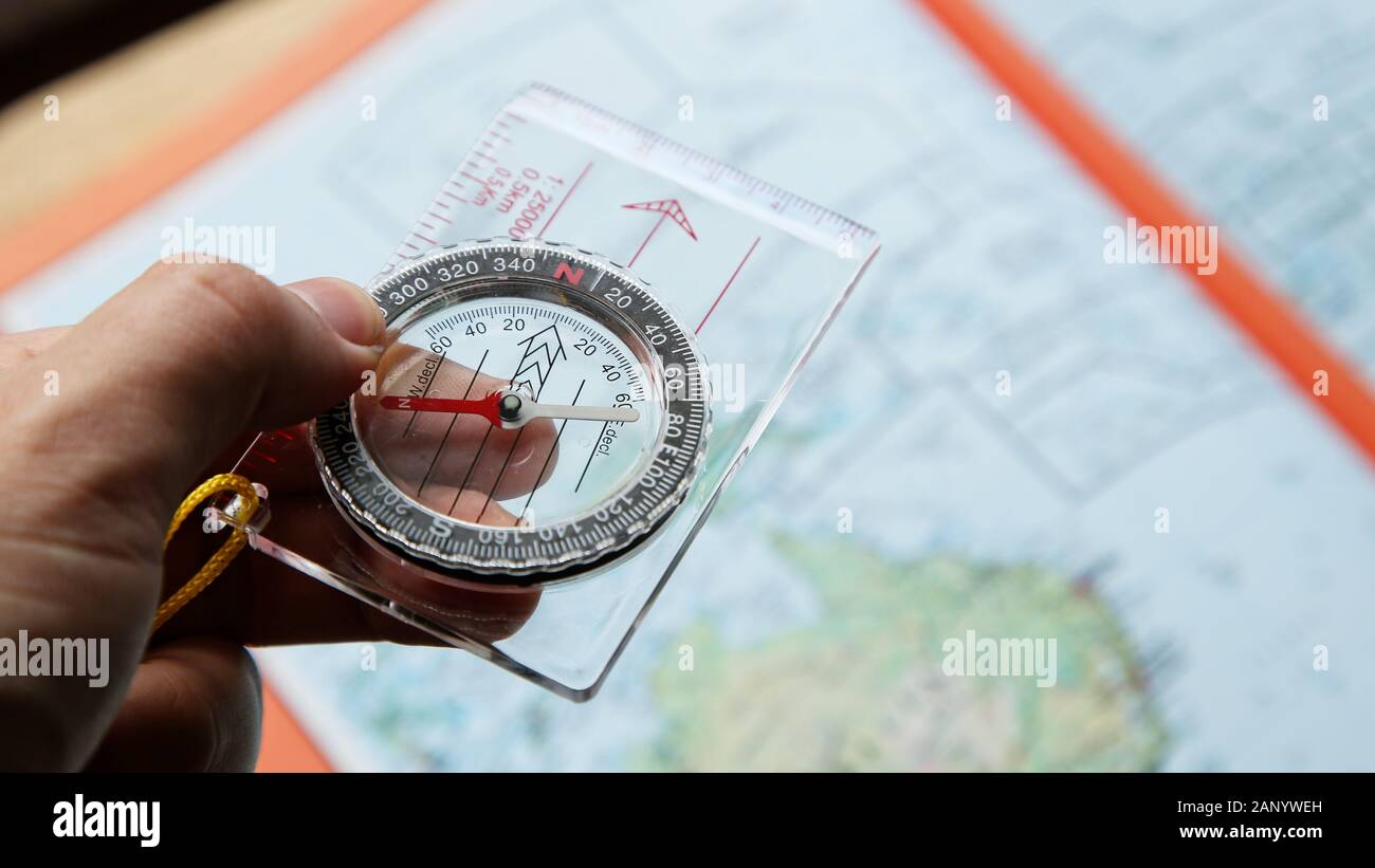 High angle shot of person holding a compass over a geographical map ...
