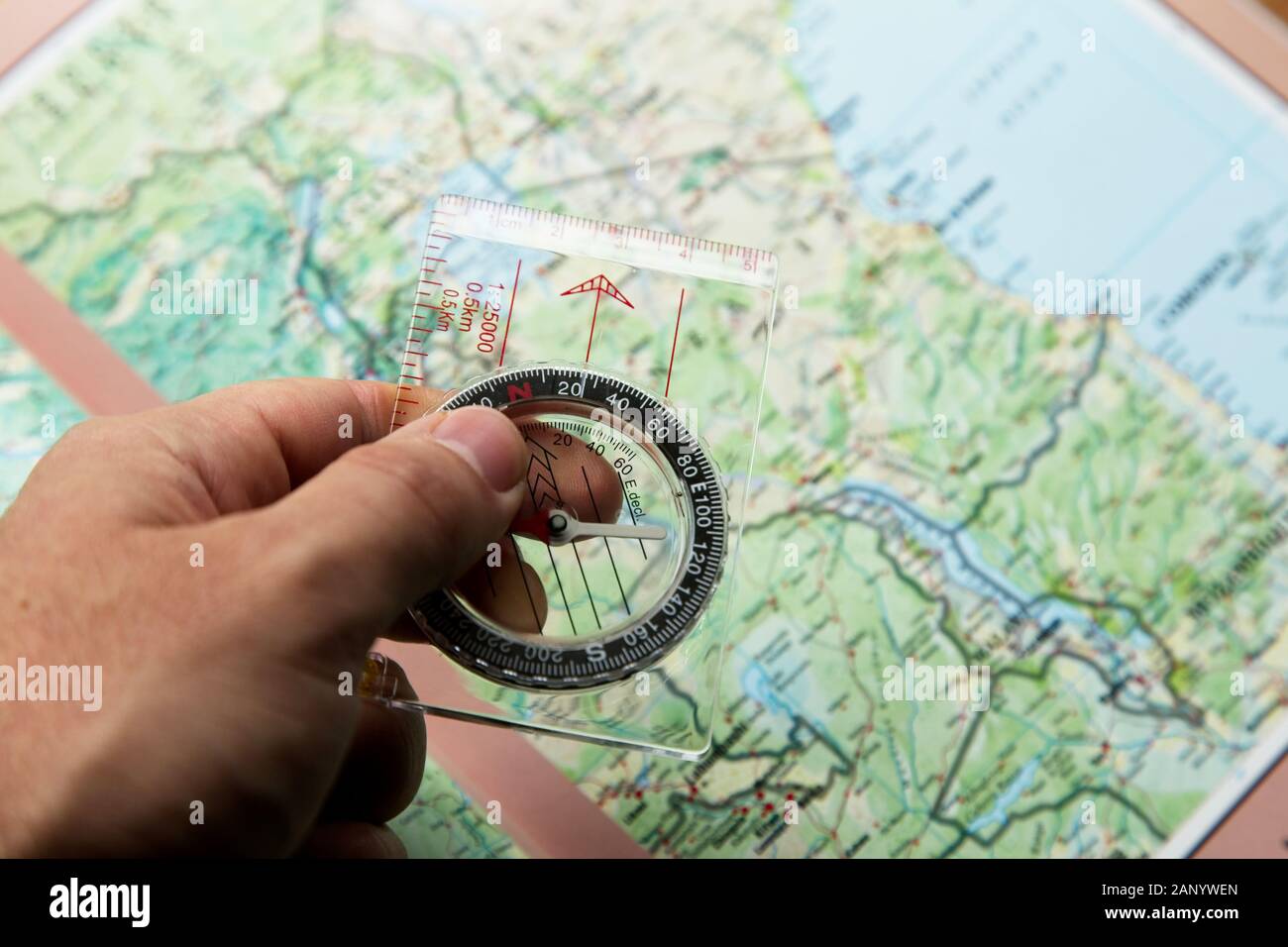 High angle shot of person holding a compass over a geographical map ...