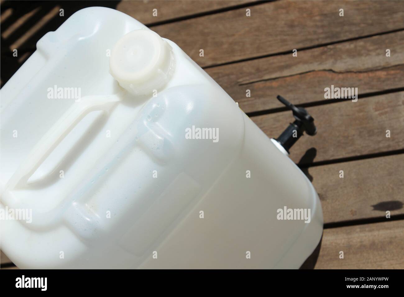 High angle shot of a white plastic water container on a wooden porch ...