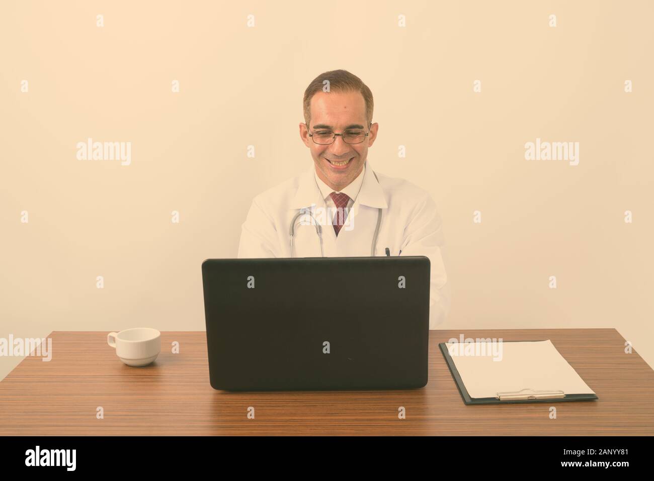 Portrait of mature Persian man doctor behind desk Stock Photo - Alamy