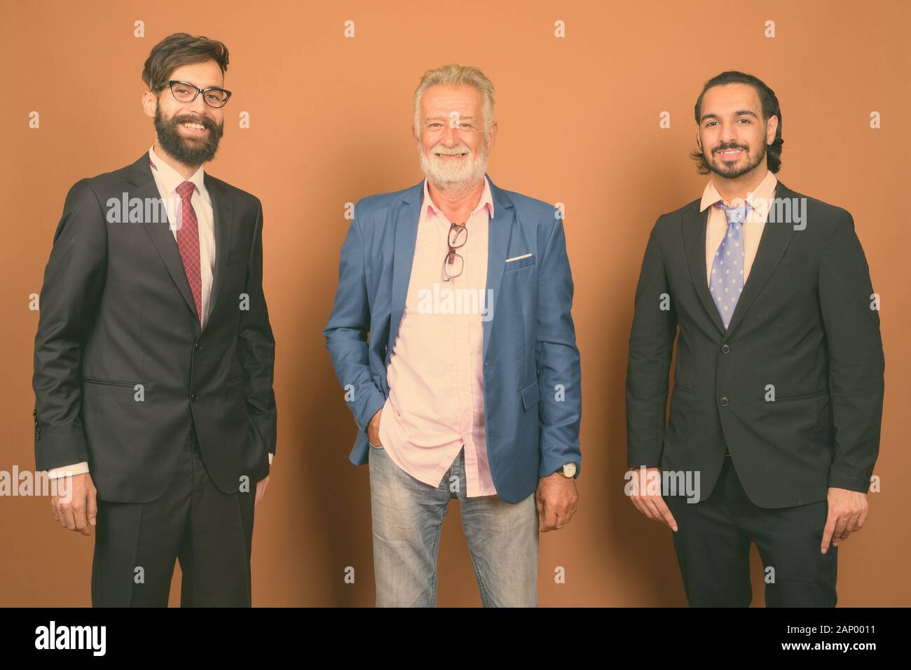 Three multi ethnic bearded businessmen together against brown ...