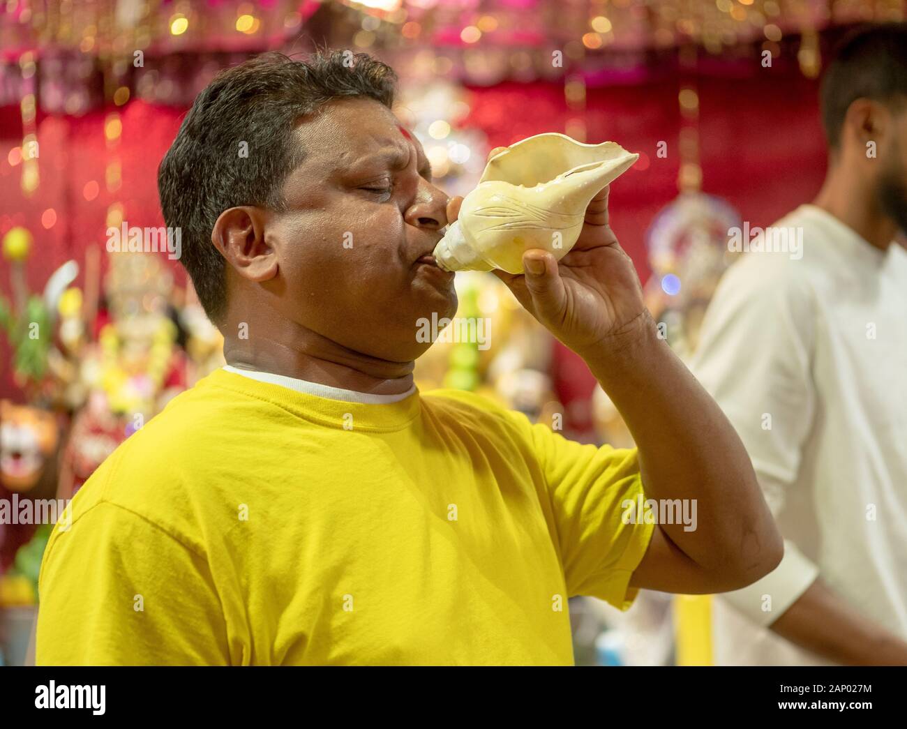 A devout Hindu worshipper blows into a conch shell during Sunday ...