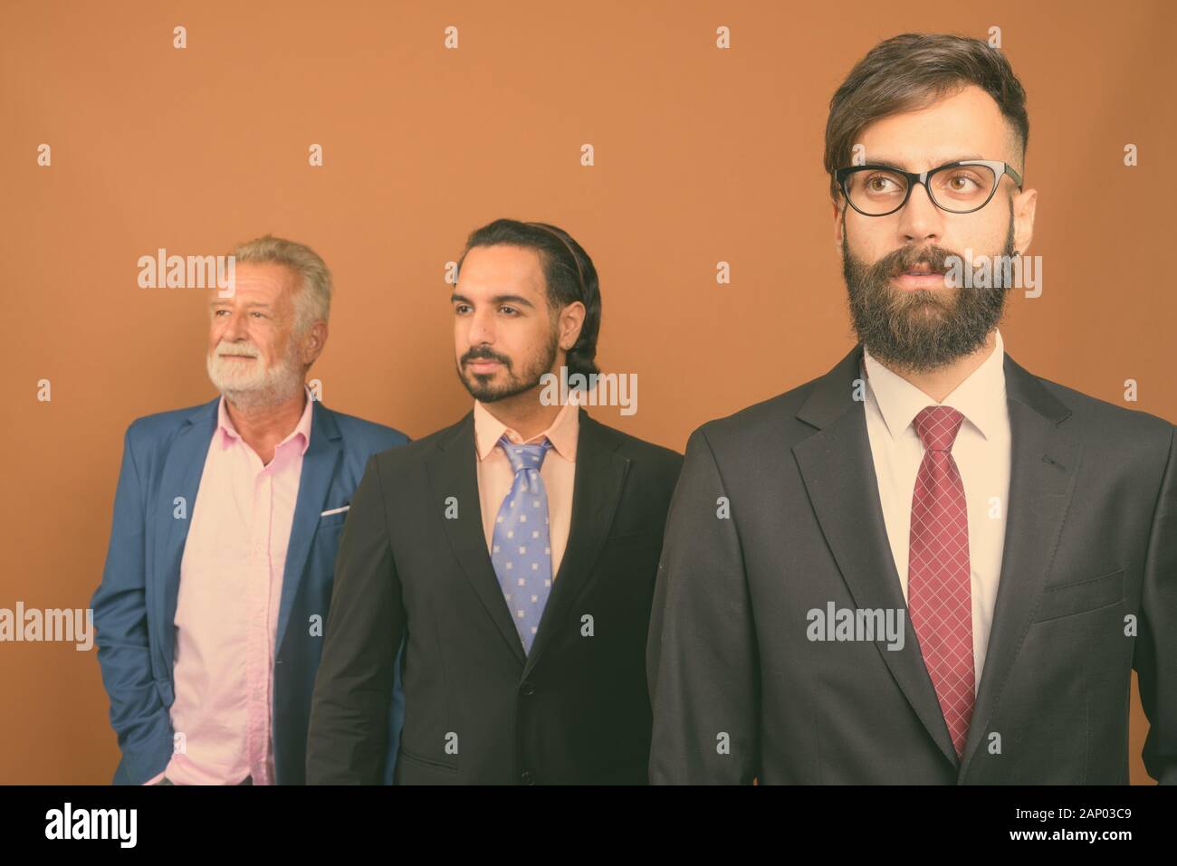 Three multi ethnic bearded businessmen together against brown ...