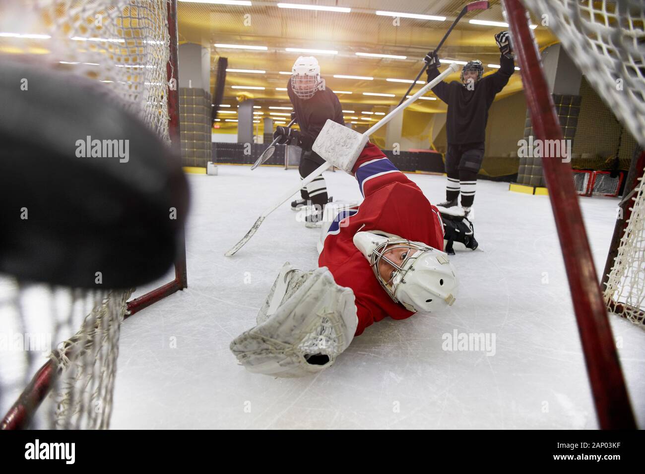 Action shot of female team playing hockey, focus on goalkeeper sliding ...