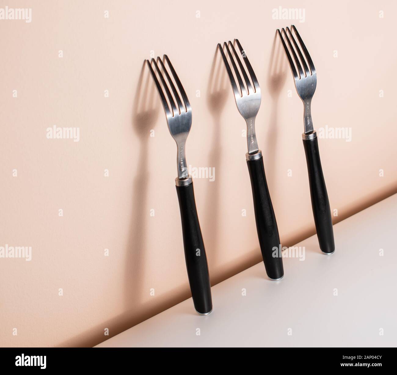 Forks standing on a wall, with big shadows between them. Silverware and ...