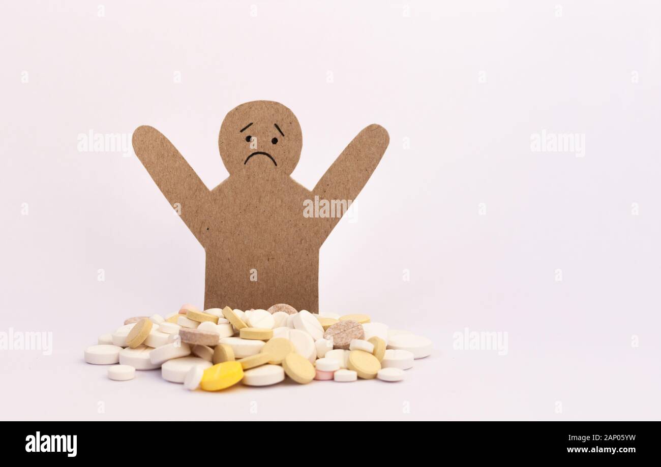 Heap of colorful pills and a figure of a cardboard man, tablets and ...