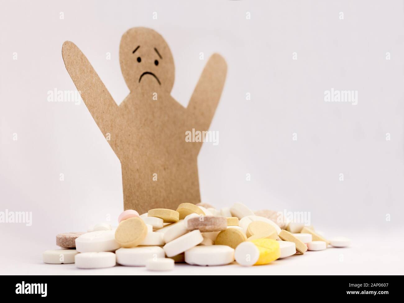 Heap of colorful pills and a figure of a cardboard man, tablets and ...