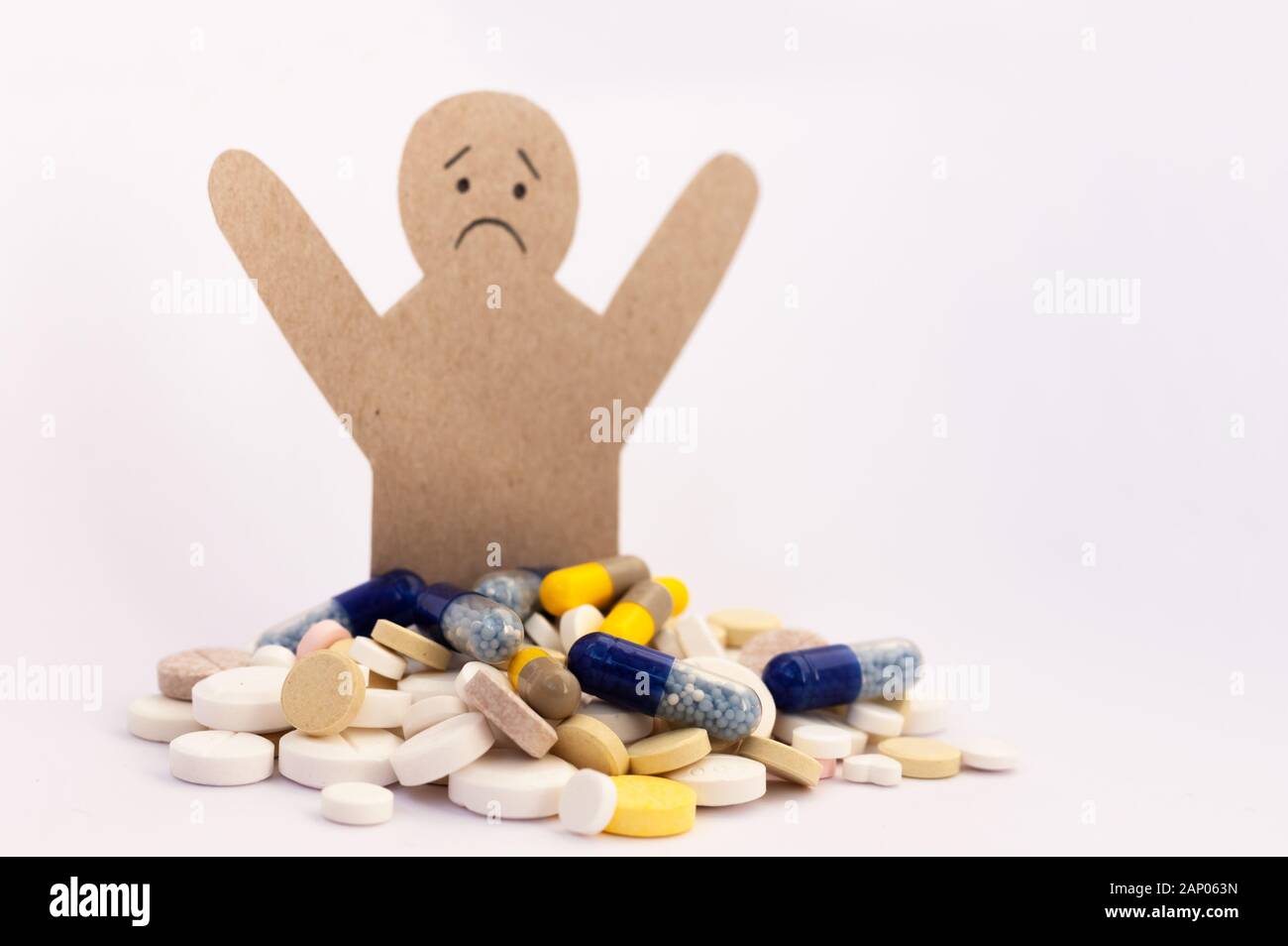Heap of colorful pills and a figure of a cardboard man, tablets and ...