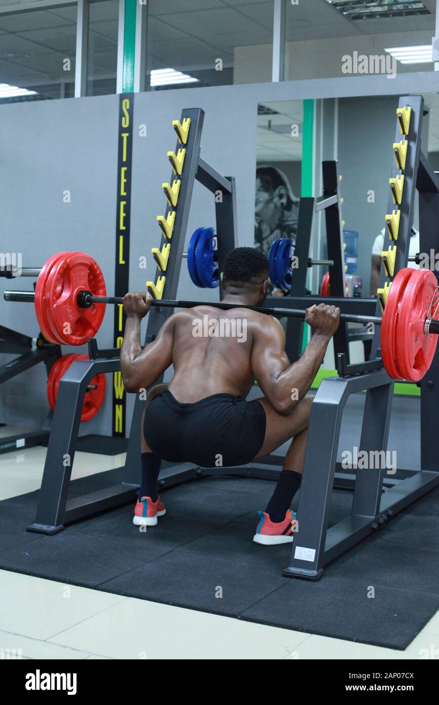 Fit young man in sportswear straining to lift heavy weights during a ...