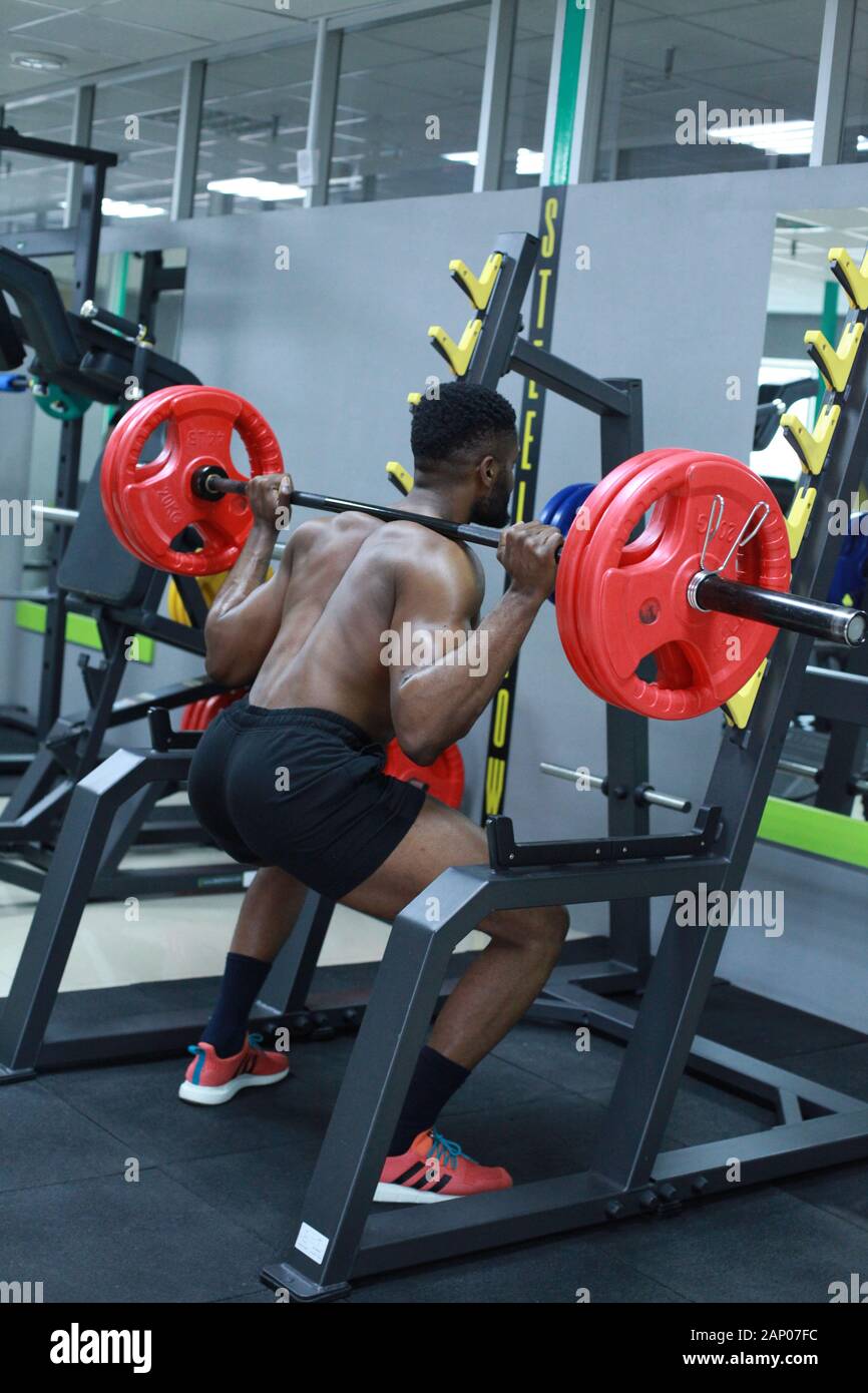 Fit young man in sportswear straining to lift heavy weights during a ...