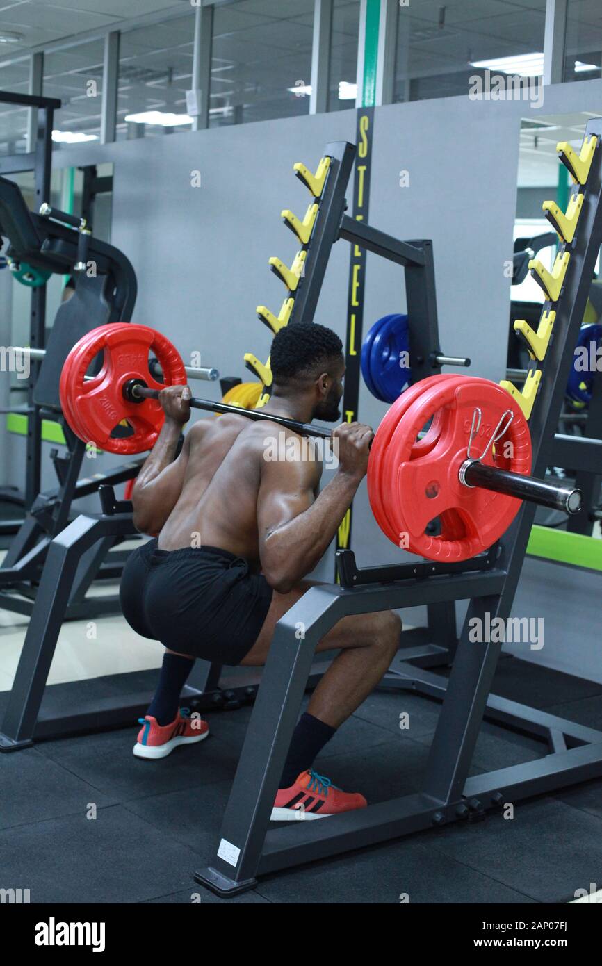Fit young man in sportswear straining to lift heavy weights during a ...