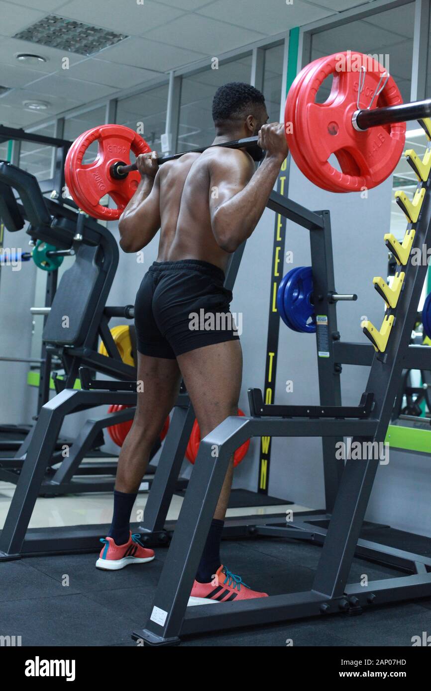 Fit young man in sportswear straining to lift heavy weights during a ...