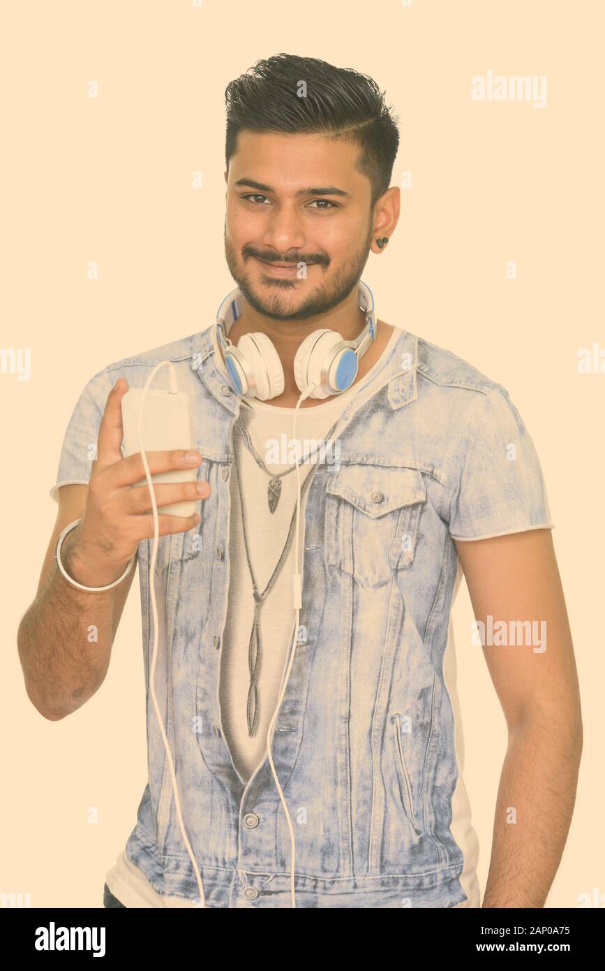 Young happy Indian man using mobile phone with headphones Stock Photo ...