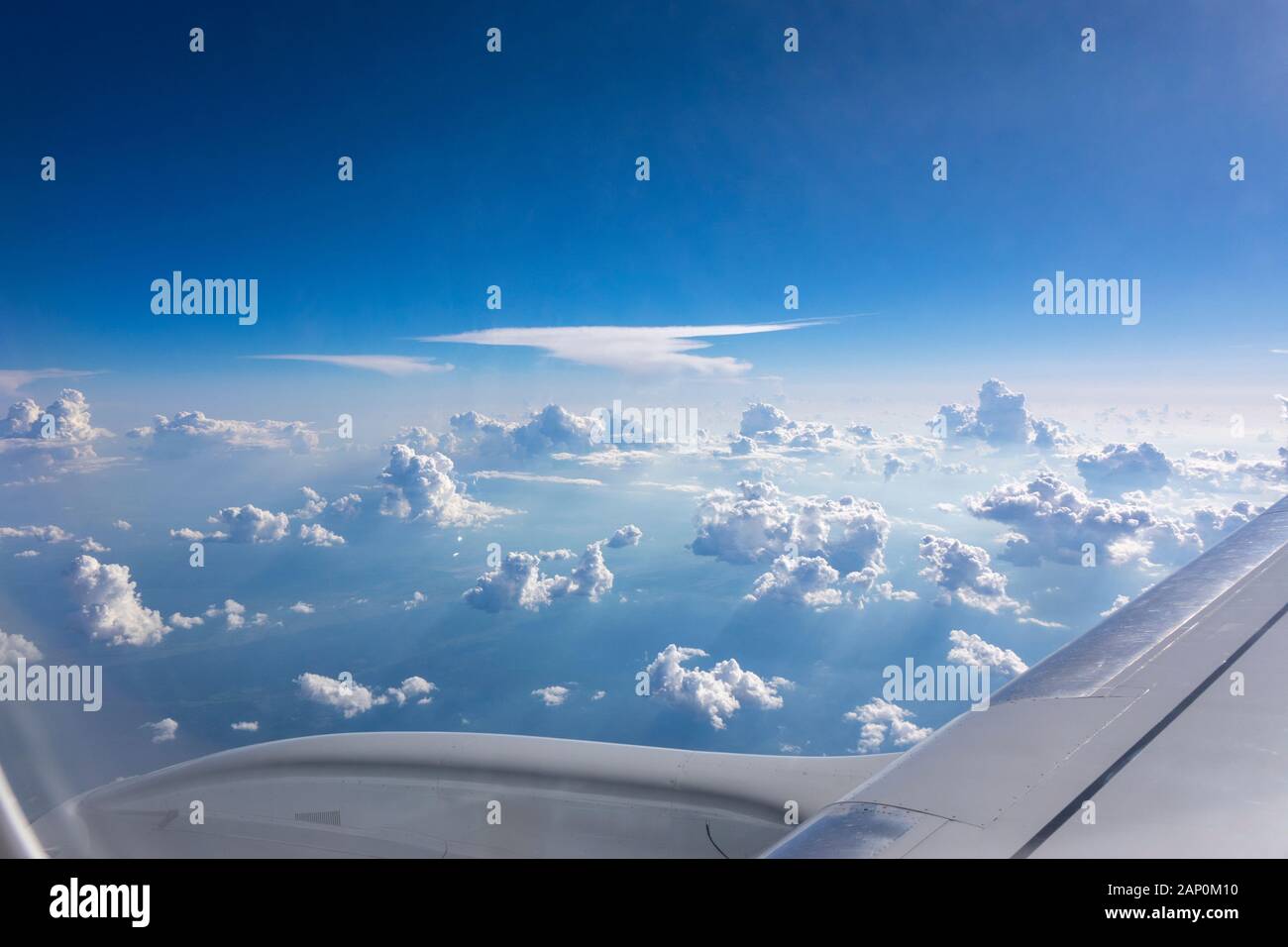 Airplane wing above fluffy white clouds in a blue sky Stock Photo - Alamy