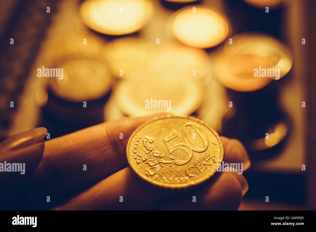 Golden 50 euro cent coin in human hand, money in female fingers, stacks ...