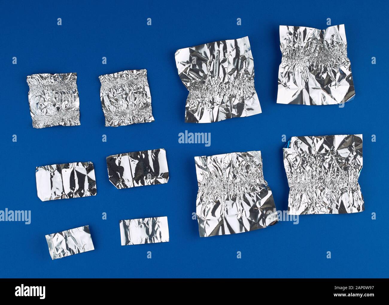 various crumpled foil used candy wrappers on a blue background, top ...