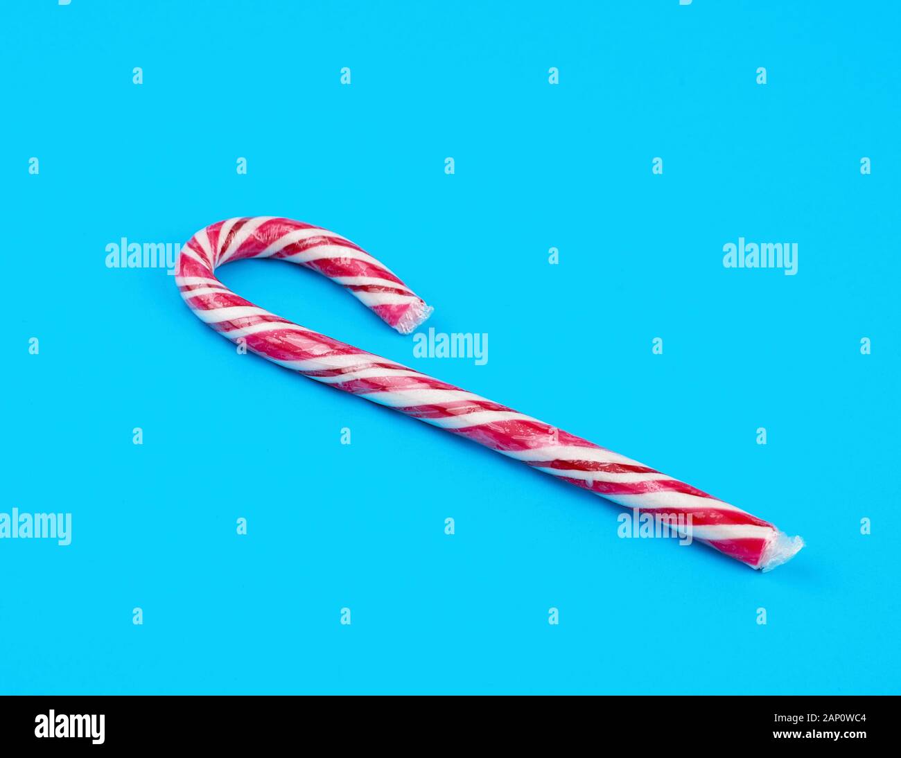 red-white candy stick in transparent cellophane on a blue background ...