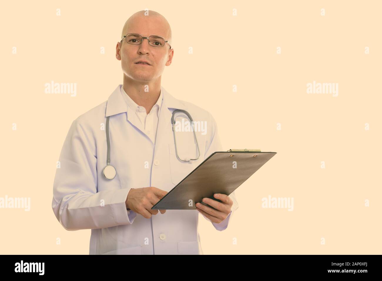 Studio shot of young handsome bald man doctor isolated against white ...