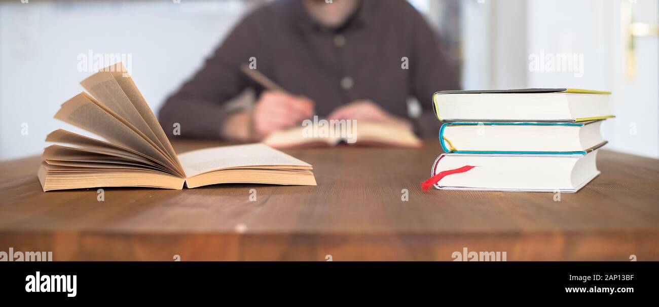 Male student researching and learning at home. Stack of books, person ...