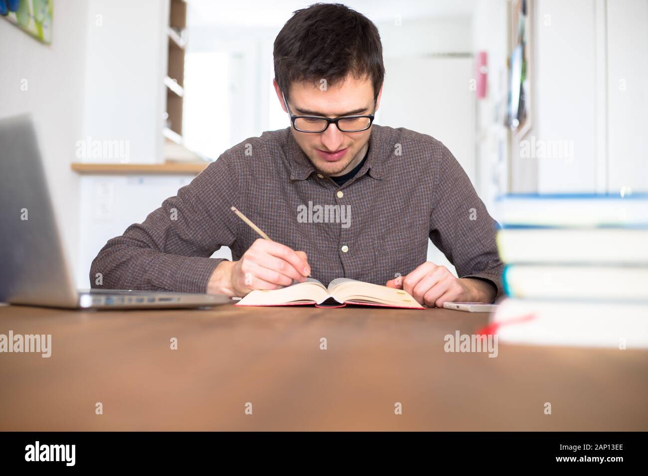 Male happy student researching and learning at home, stack of books ...