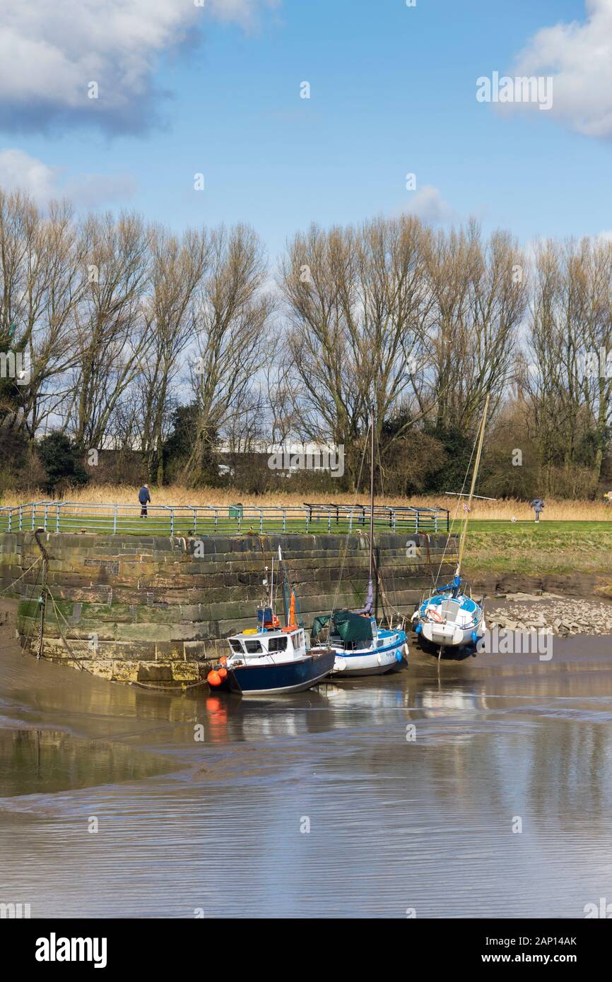Small boats moored at quay at low tide on the River Mersey at Widnes ...