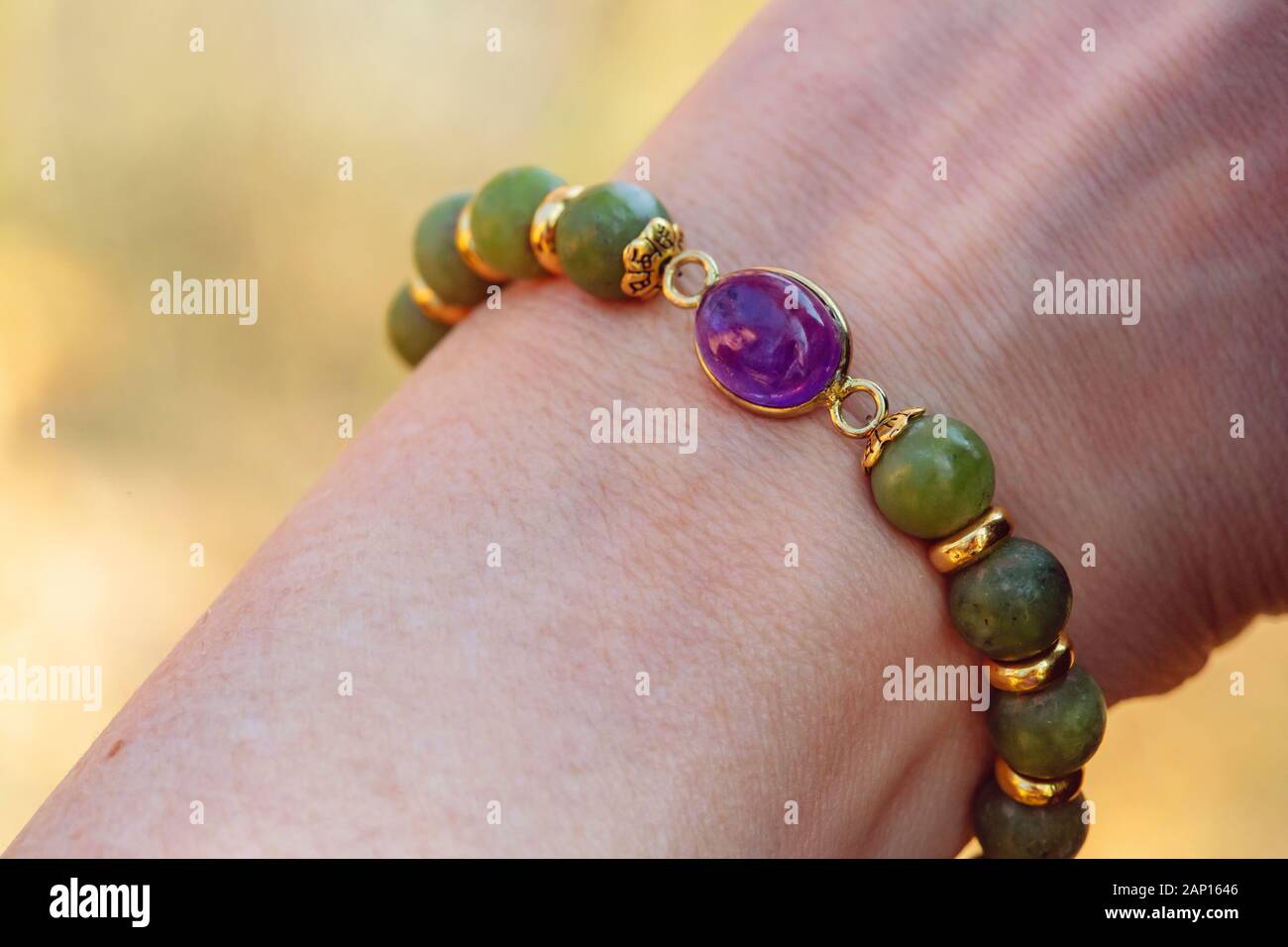 male hand with natural mineral stone bracelet in nature forest ...