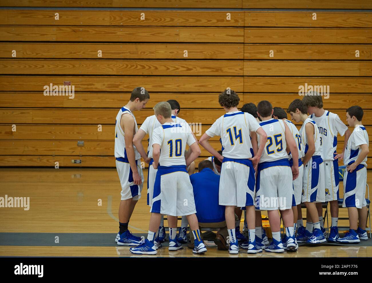 high school basketball team surrounding coach for strategy meeting ...