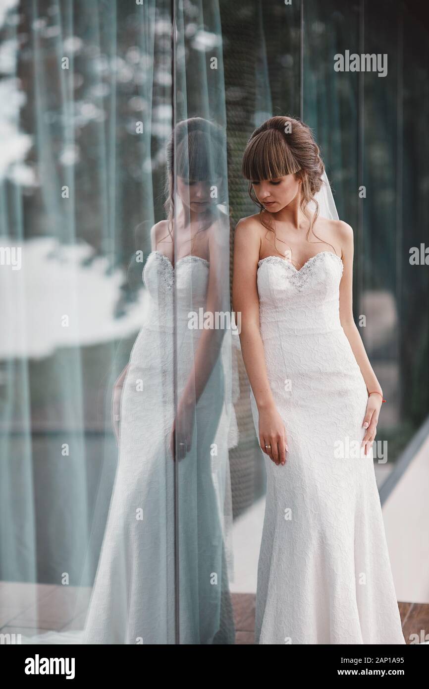 Wedding day. Bride portrait in white dress by the window outside ...