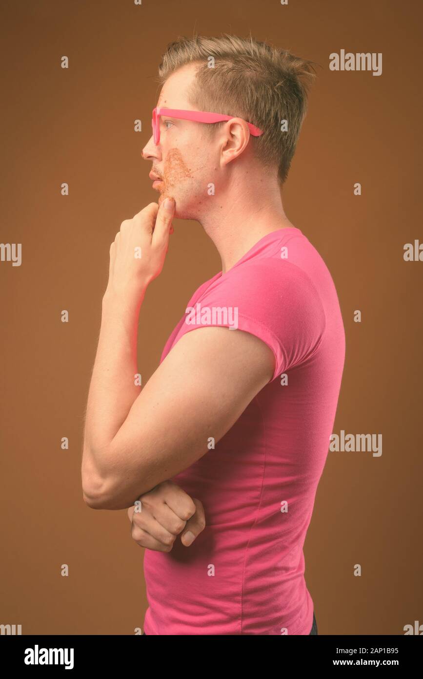 Studio shot of young handsome nerd man eating chocolate cake as messy ...